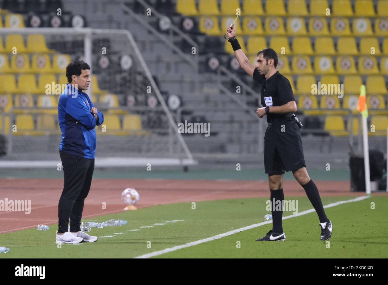 Al Arabi manager, Younes Ali, is shown a yellow card for dissent during ...
