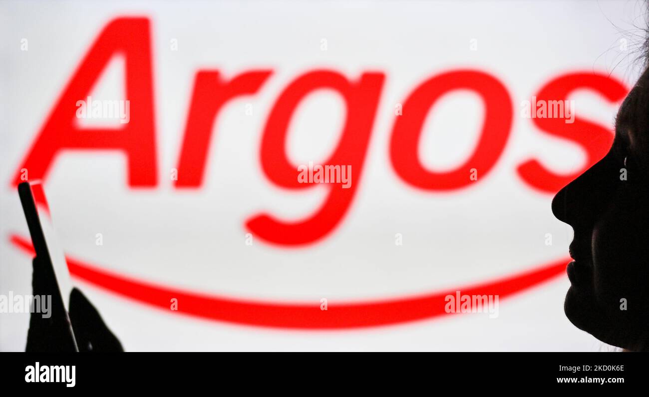 An image of a woman holding a cell phone in front of the Argos logo ...