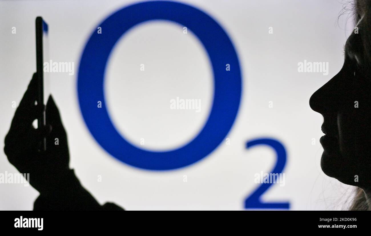 An image of a woman holding a cell phone in front of the O2 logo ...