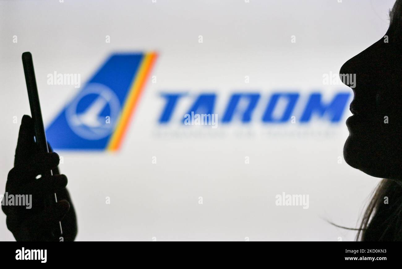 An image of a woman holding a cell phone in front of the TAROM Airline ...