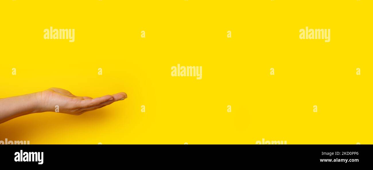 hand with palm up over yellow background, place for your advertisement ...