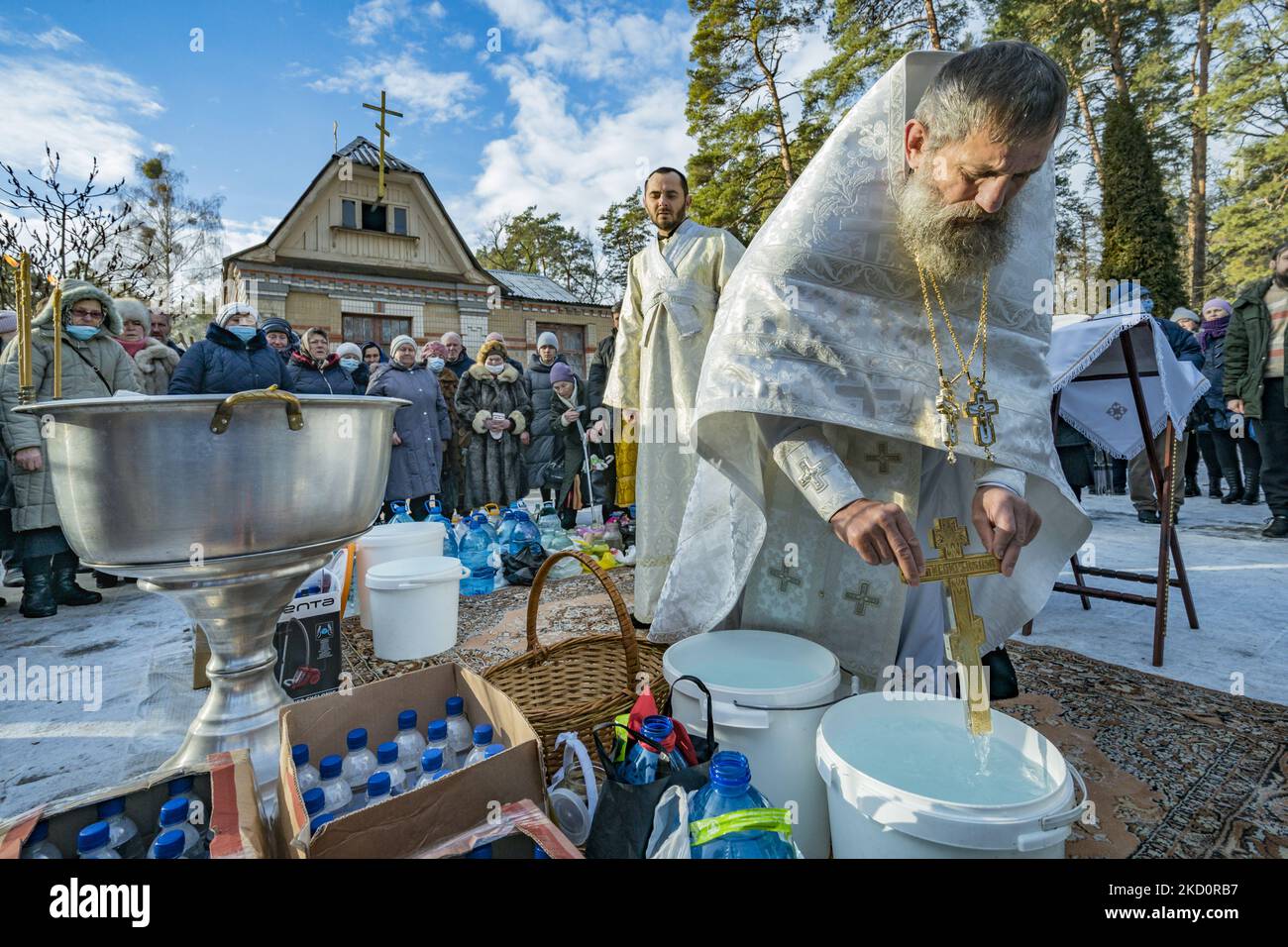 Orthodox priest dips a holy cross in water brought by his congreagation ...