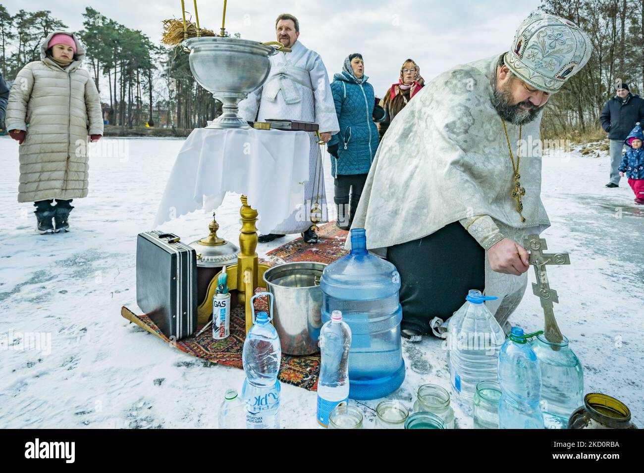 Orthodox priest dips a holy cross in water brought by his congreagation ...