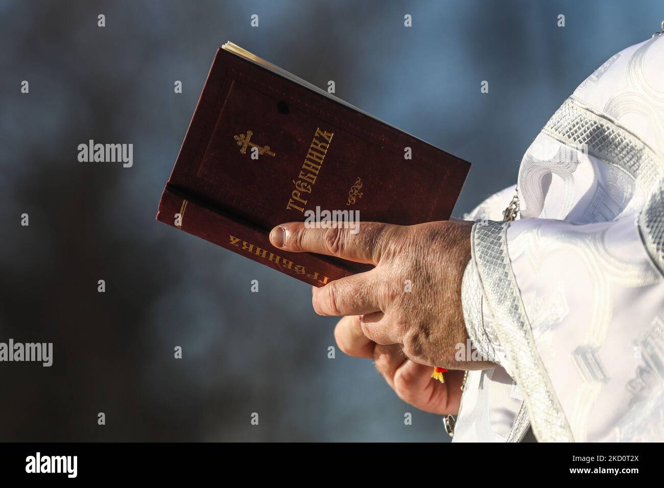 A priest of the Eastern Orthodox Church holds the Euchologion book ...