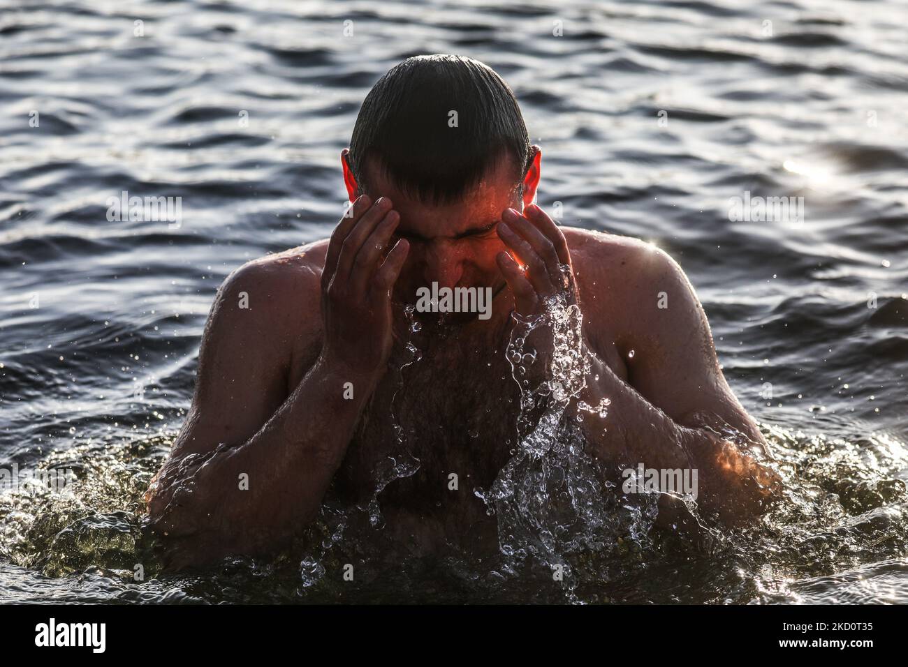 A member of the Eastern Orthodox Church prays while taking a bath in ...