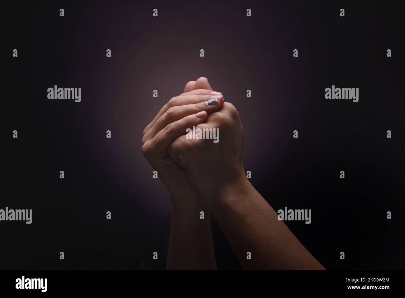 Praying hands with faith in religion and belief in God over dark ...