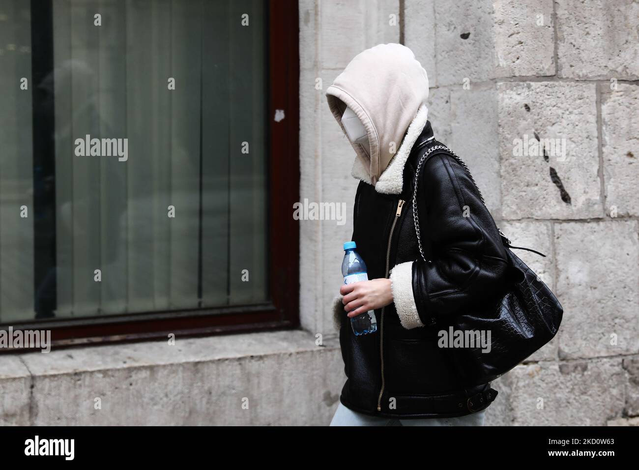A person wearing a protective face mask walks the street in Krakow ...