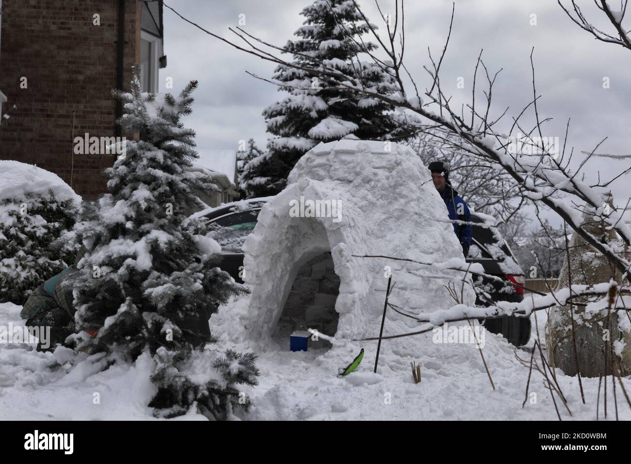 A father and his children construct a large igloo out of snow on the ...