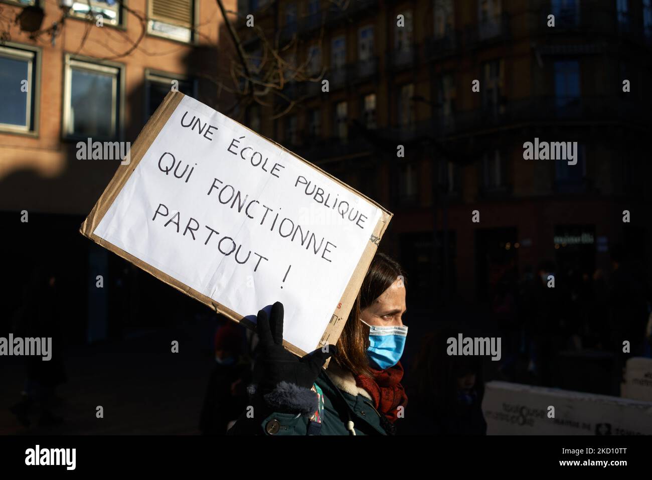 A mother holds a cardboard reading 'for a public school running well ...