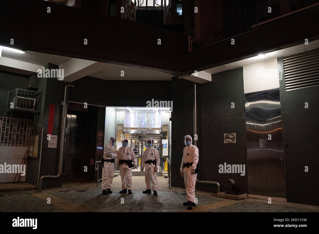 Four police officers in white protective suits stand outside a ...