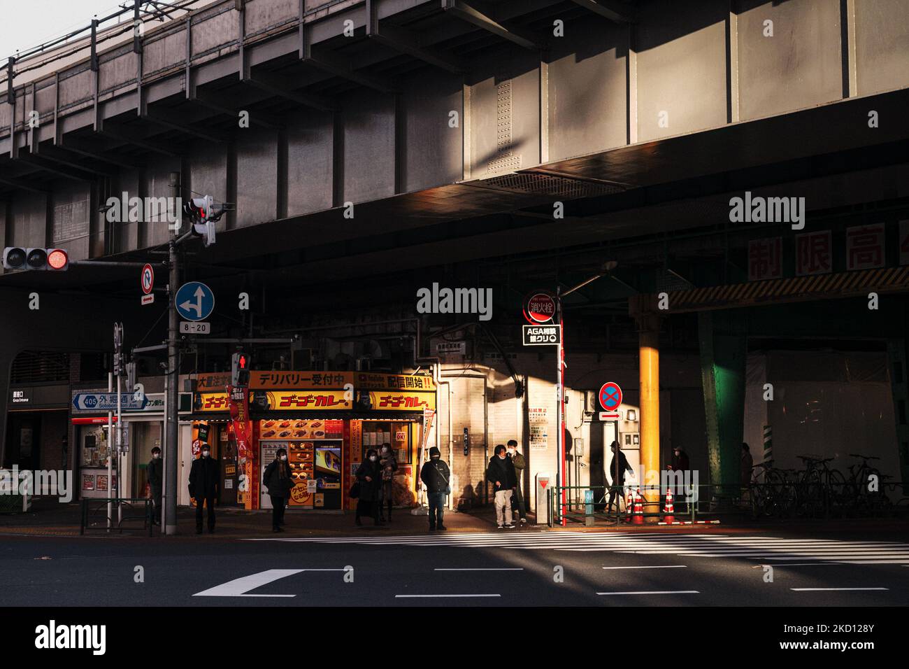 People wearing masks wait for a traffic light at the intersection of ...