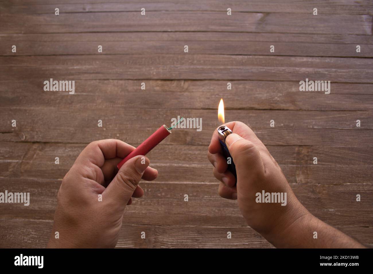 Image of the hands of a man who lights the fuse of a firecracker with a ... Image of the hands of a man who lights the fuse of a firecracker with a ...
