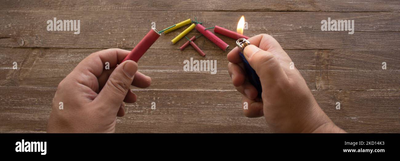 Image of the hands of a man who lights the fuse of a firecracker with a ...