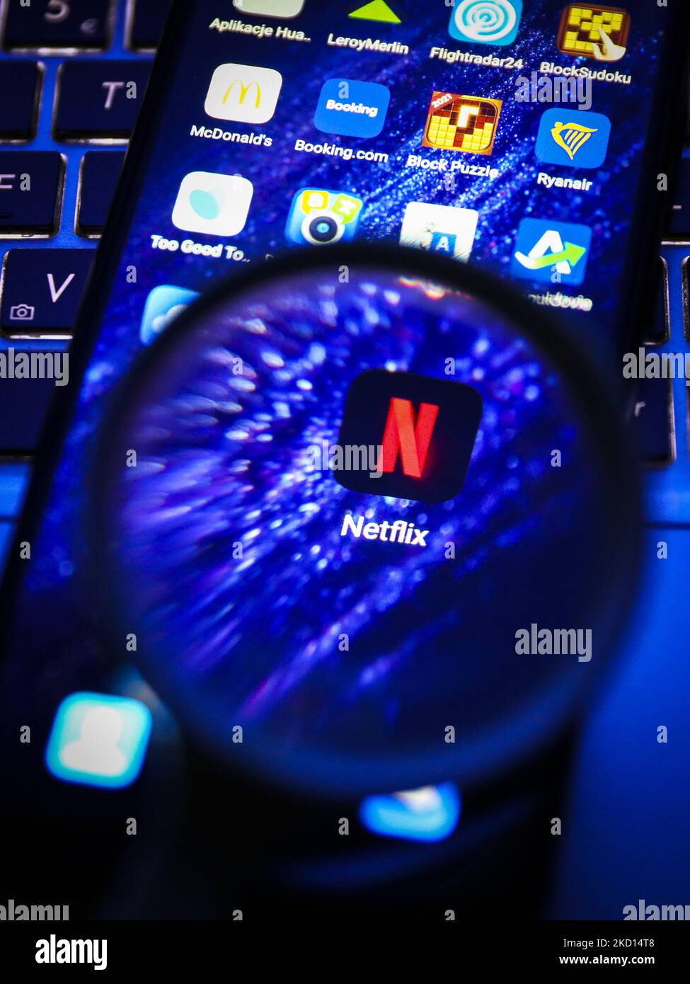 Netflix app is seen through a magnifying glass while being displayed on ...