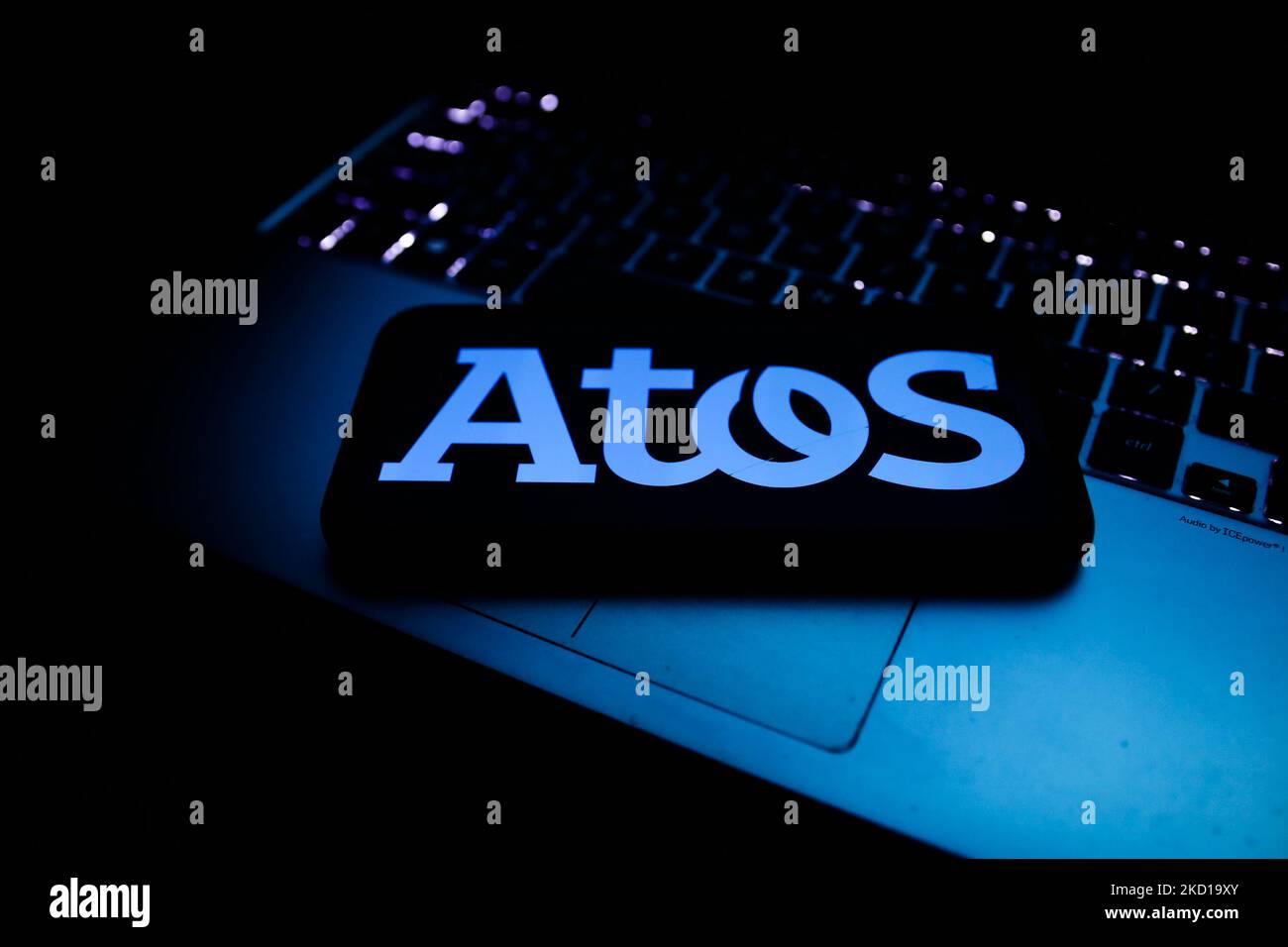 Atos logo displayed on a phone screen and a laptop keyboard are seen in ...