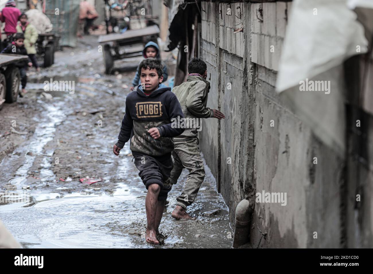 Palestinian children living in slums play in the street during cold ...