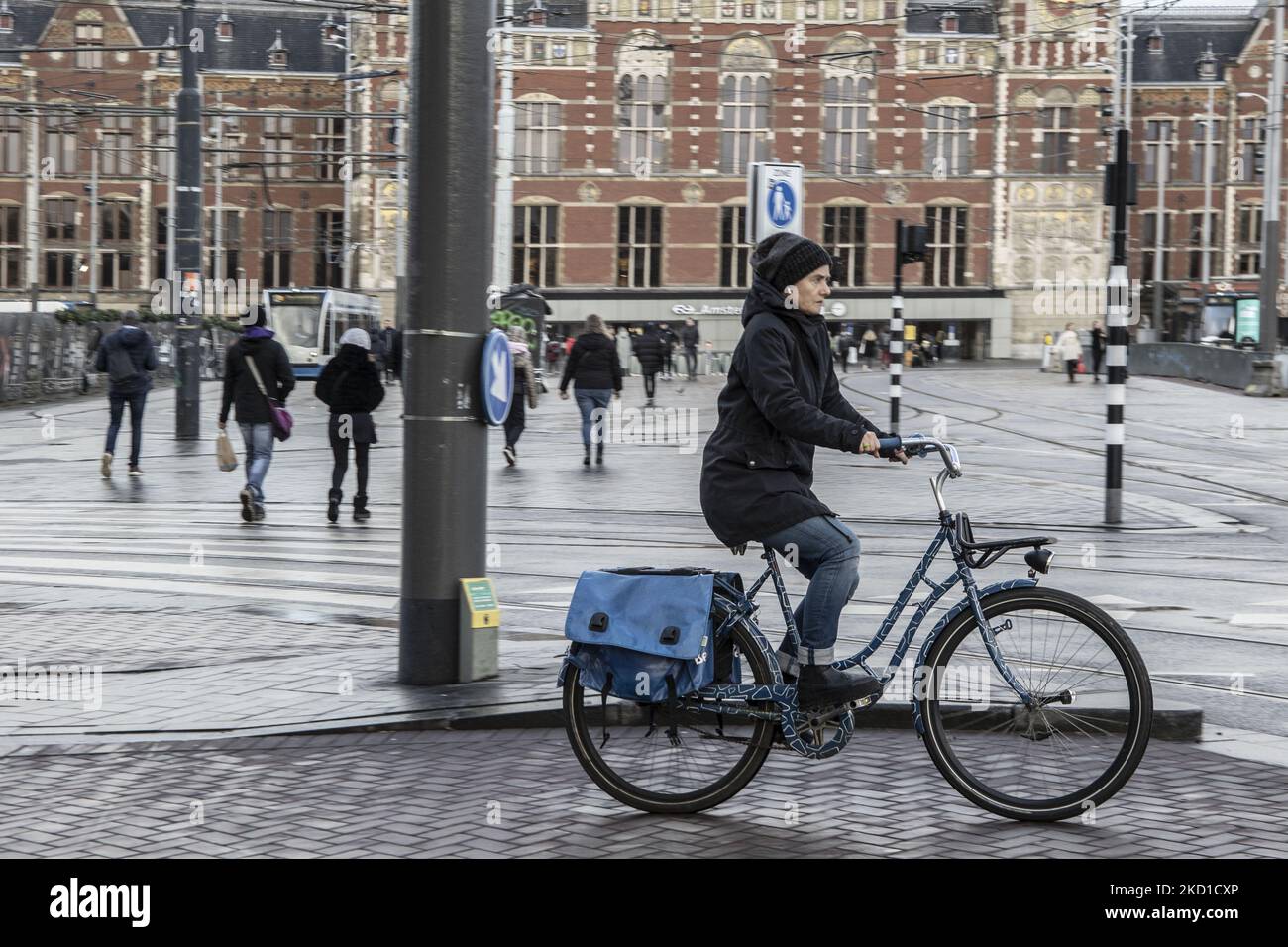 A woman as seen riding her bike with the Amsterdam central station in ...