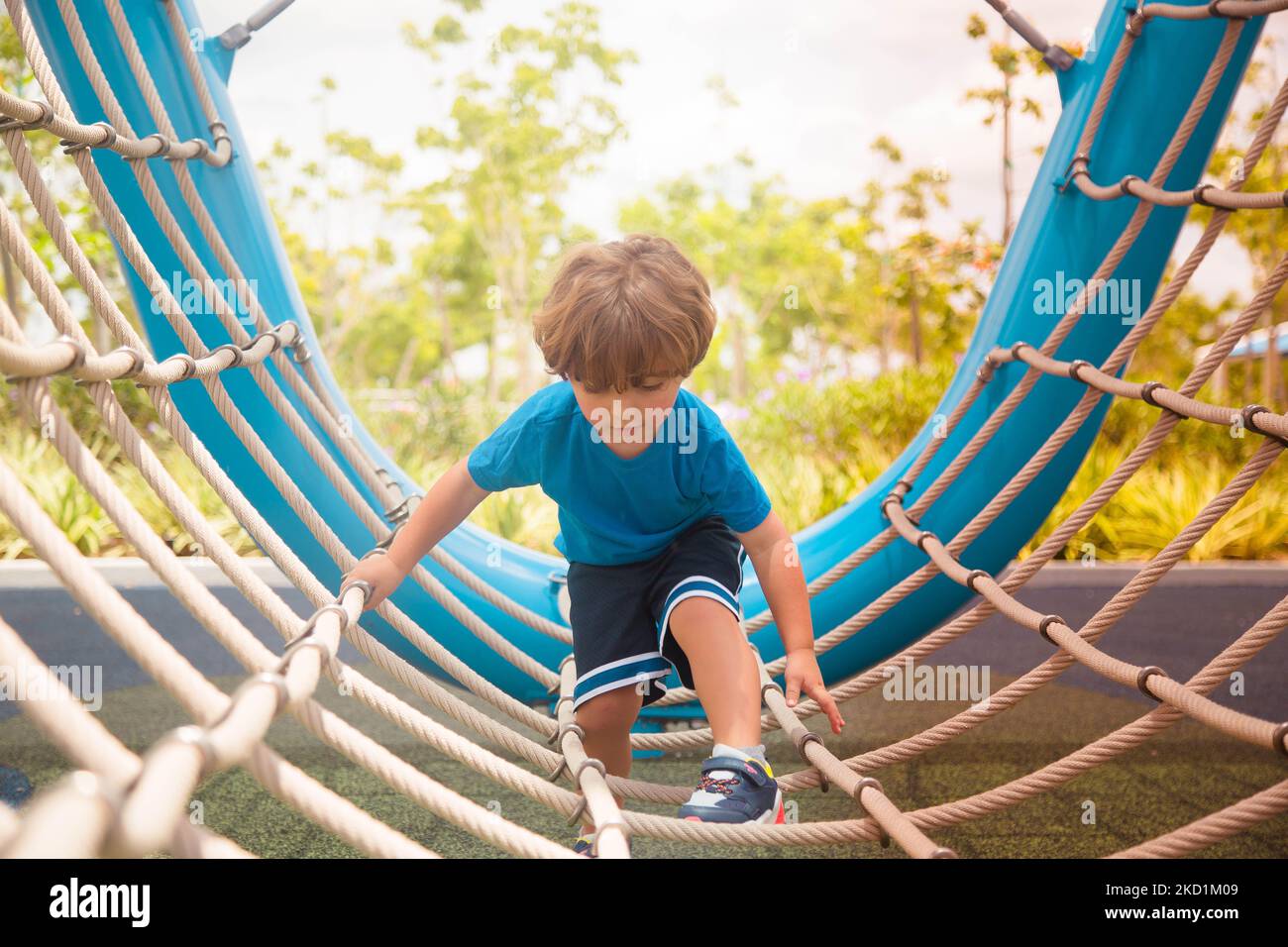 A little Caucasian boy climbing in a playground in Baker park in Naples ...