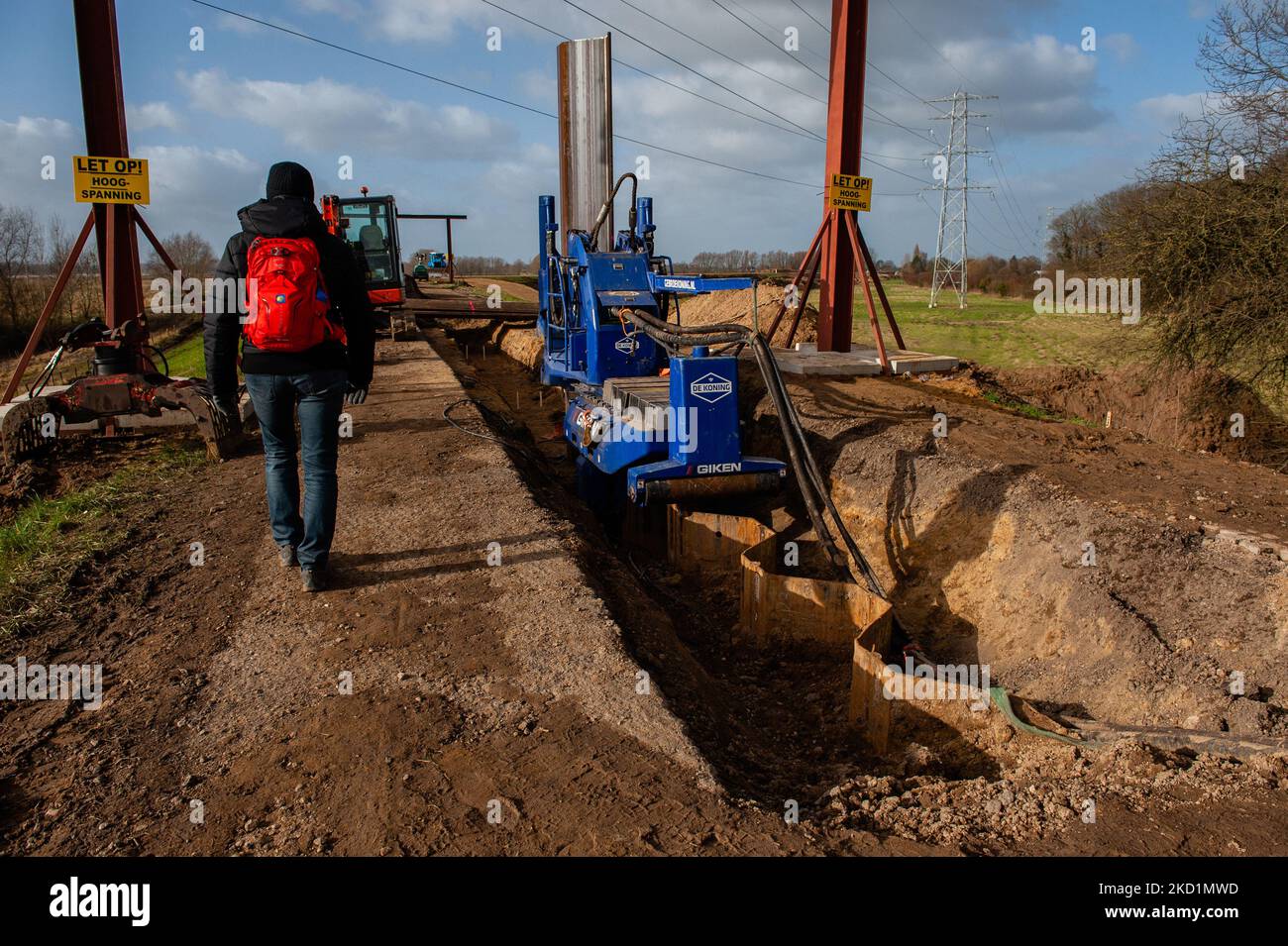 A man is passing by close to the machine introducing the sheet piles ...