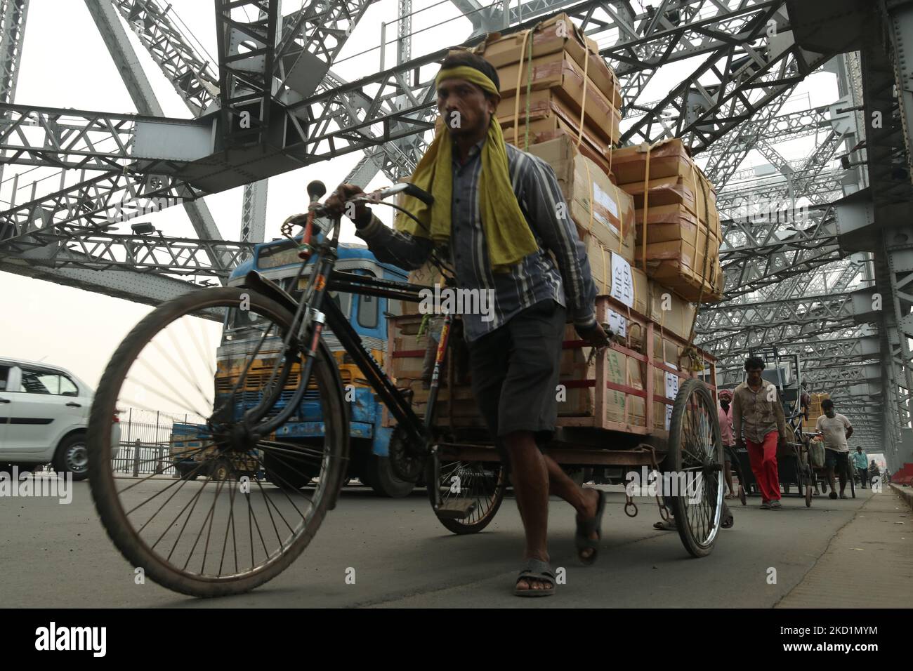 Indian Laborers push a cycle van loaded Goods across the Howrah Bridge ...