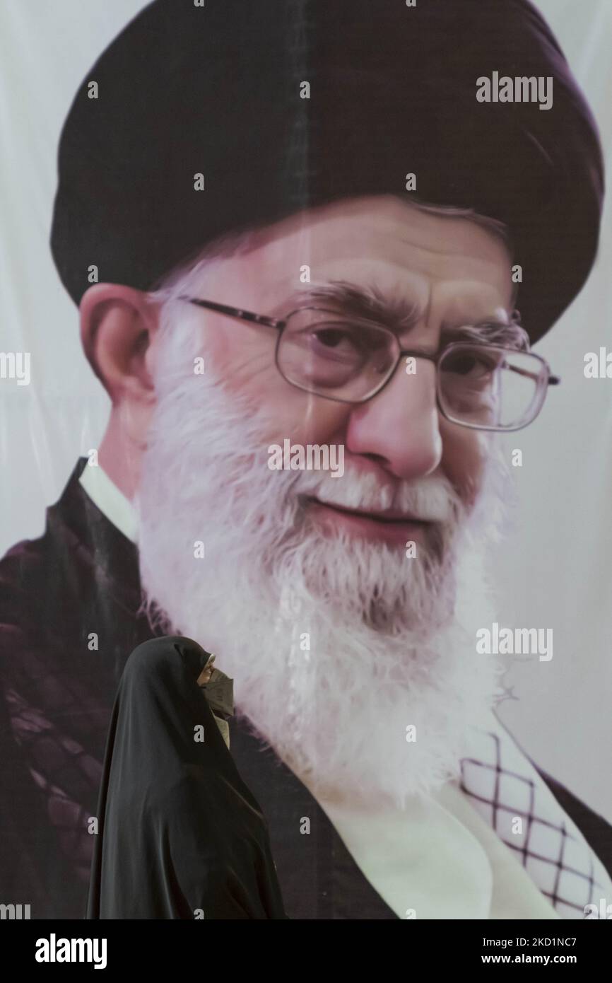 An Iranian veiled woman stands in front of a portrait of Iran’s Supreme ...