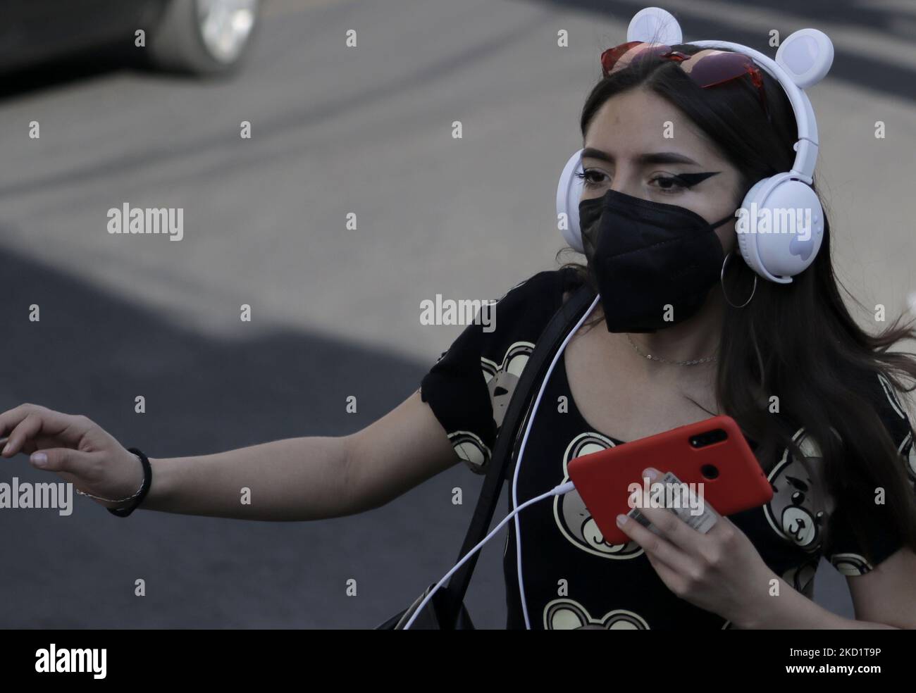 A woman wears cat-ear headphones in the streets of Mexico City during ...