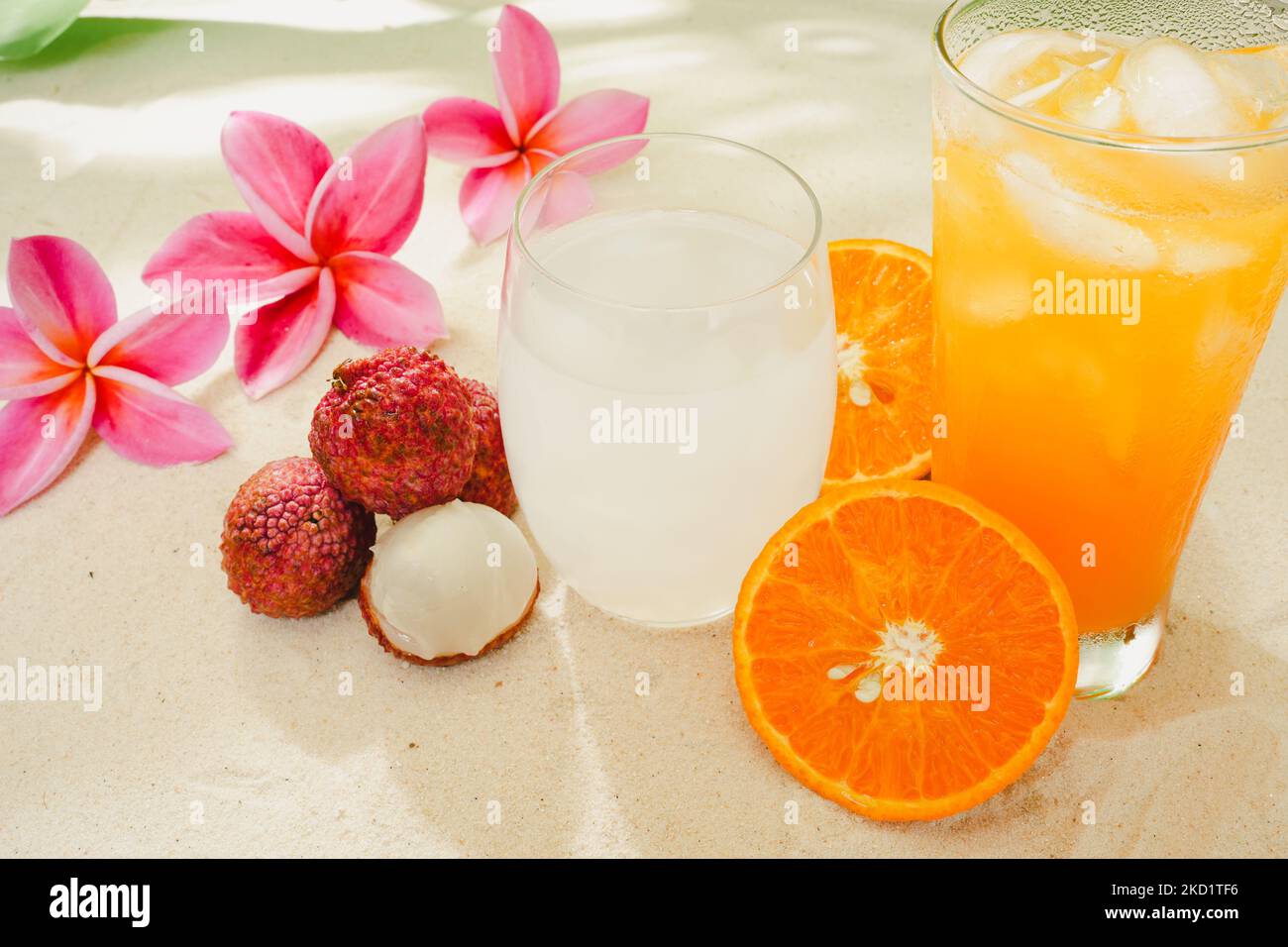 A closeup shot of a glass of orange juice and a cocktail next to lychee ...