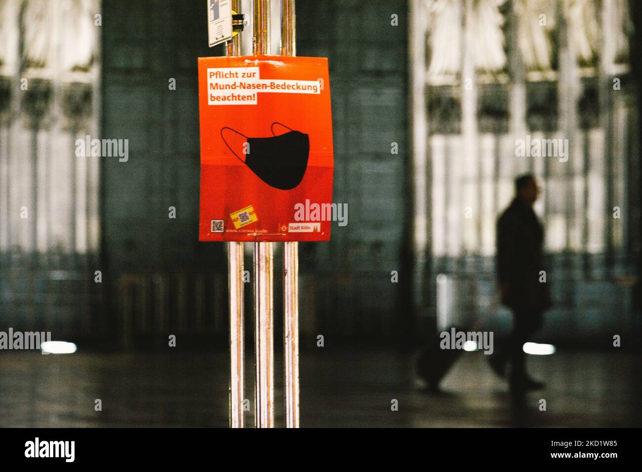 mask sign is seen in front of Dom Cathedral as a traveler walks pass by ...