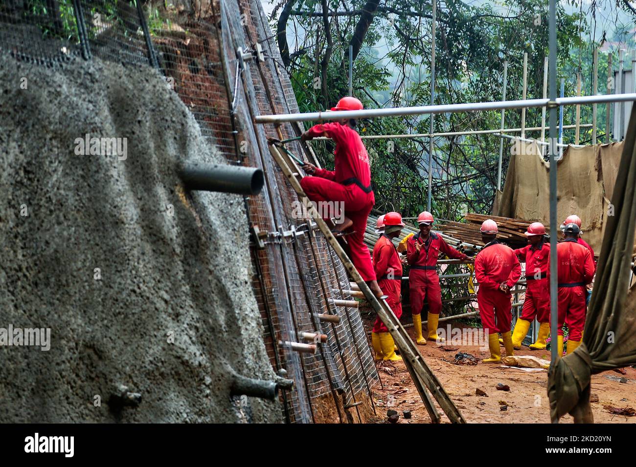 Workers competing the construction of a large retaining wall near a dam ...