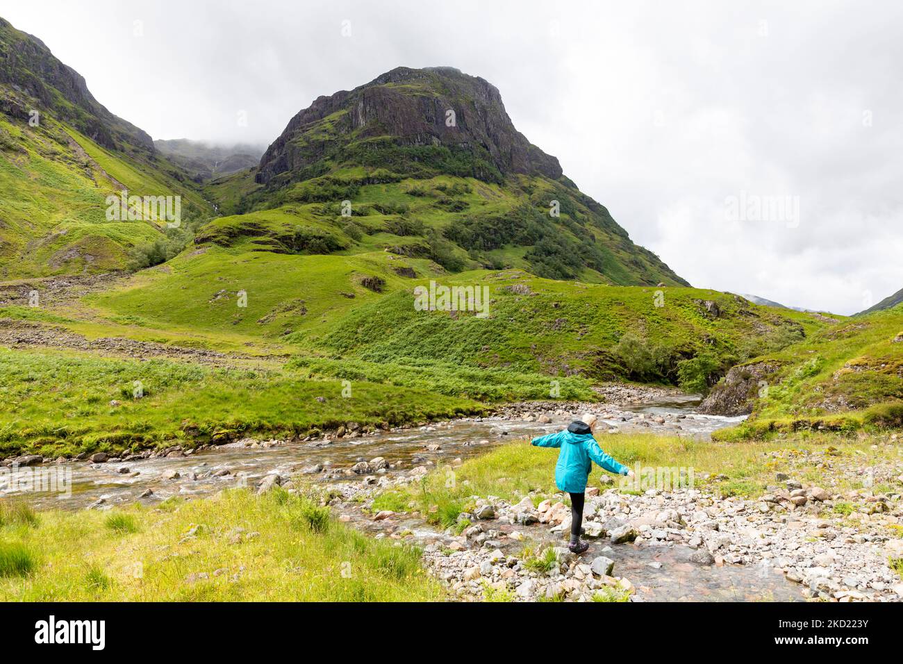 Glencoe Scotland, middle aged female blonde hiker walking by a stream ...