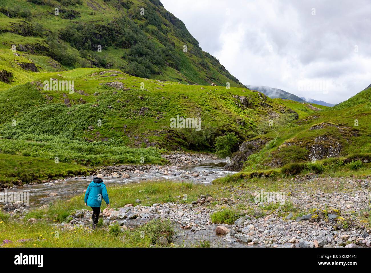 Glencoe Scotland, middle aged female blonde hiker walking by a stream ...