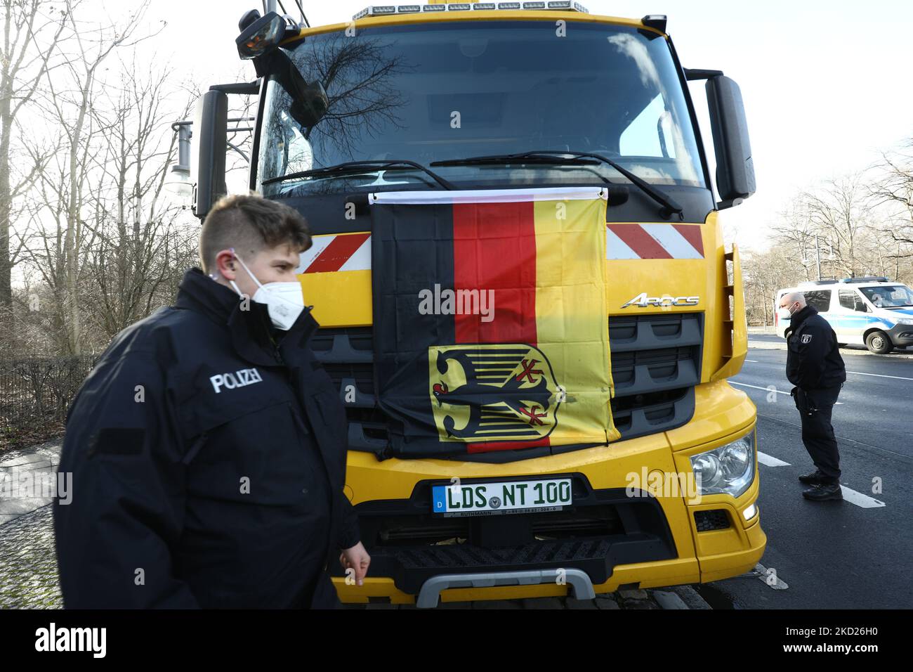 A policeman wearing a face mask walks past a truck with a German flag ...