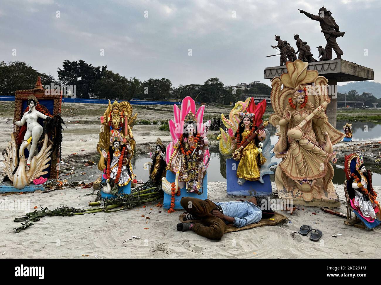 A person sleeping next to idols of Hindu God and Goddess which are ...