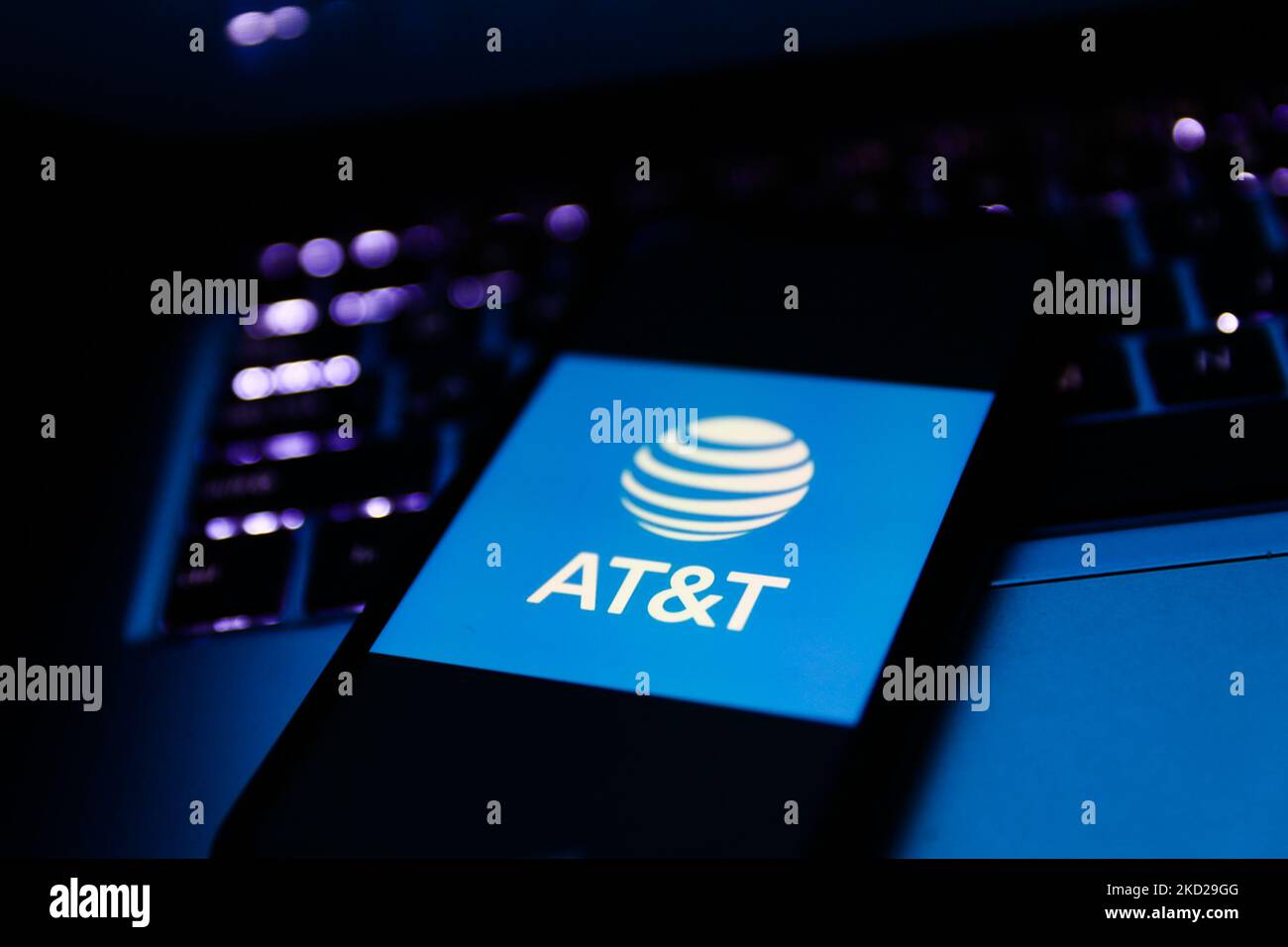AT&T logo displayed on a phone screen and a laptop keyboard are seen in ...