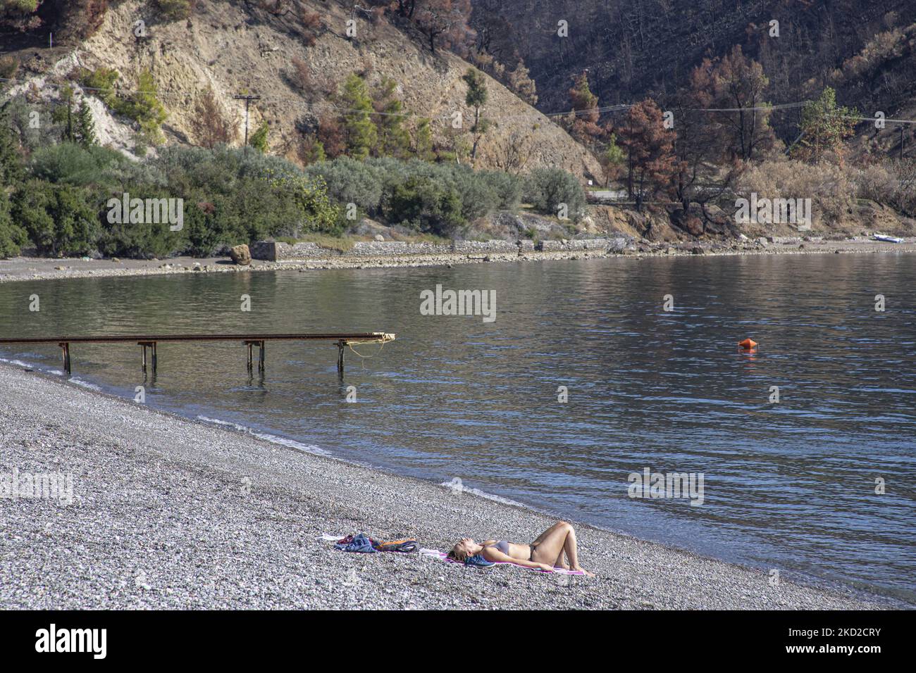 Sunny day and calm sea at Kohili beach, with pebble while a woman ...