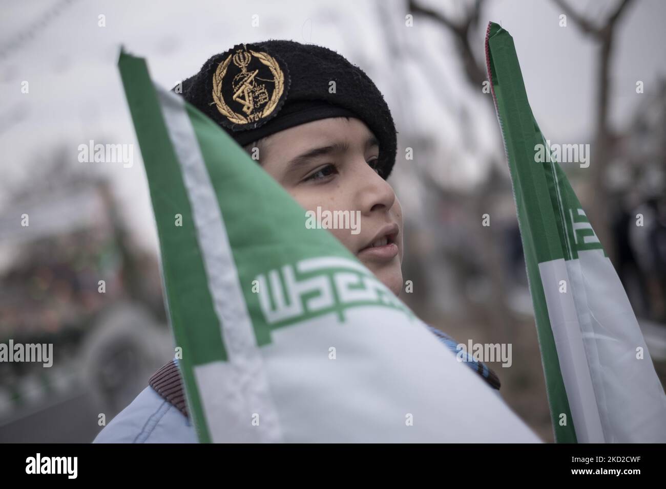 An Iranian young boy wearing a military hat with an emblem of the ...