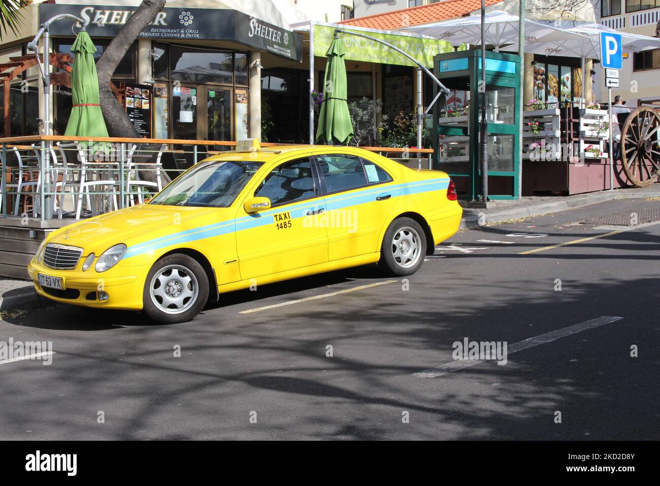 Yellow Taxi with a blue stripe parked on the side of the road in ...