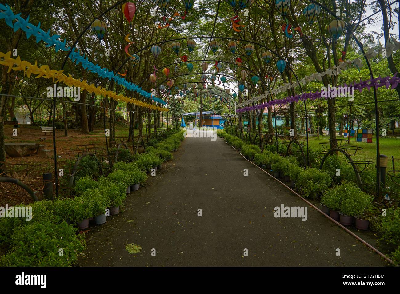 A walkway under a metallic arch with colorful wind wheels in a park ...