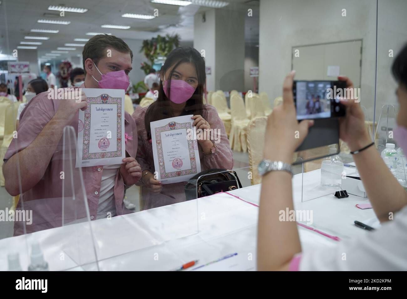 A couple wear protective face masks has their photo taken with their ...