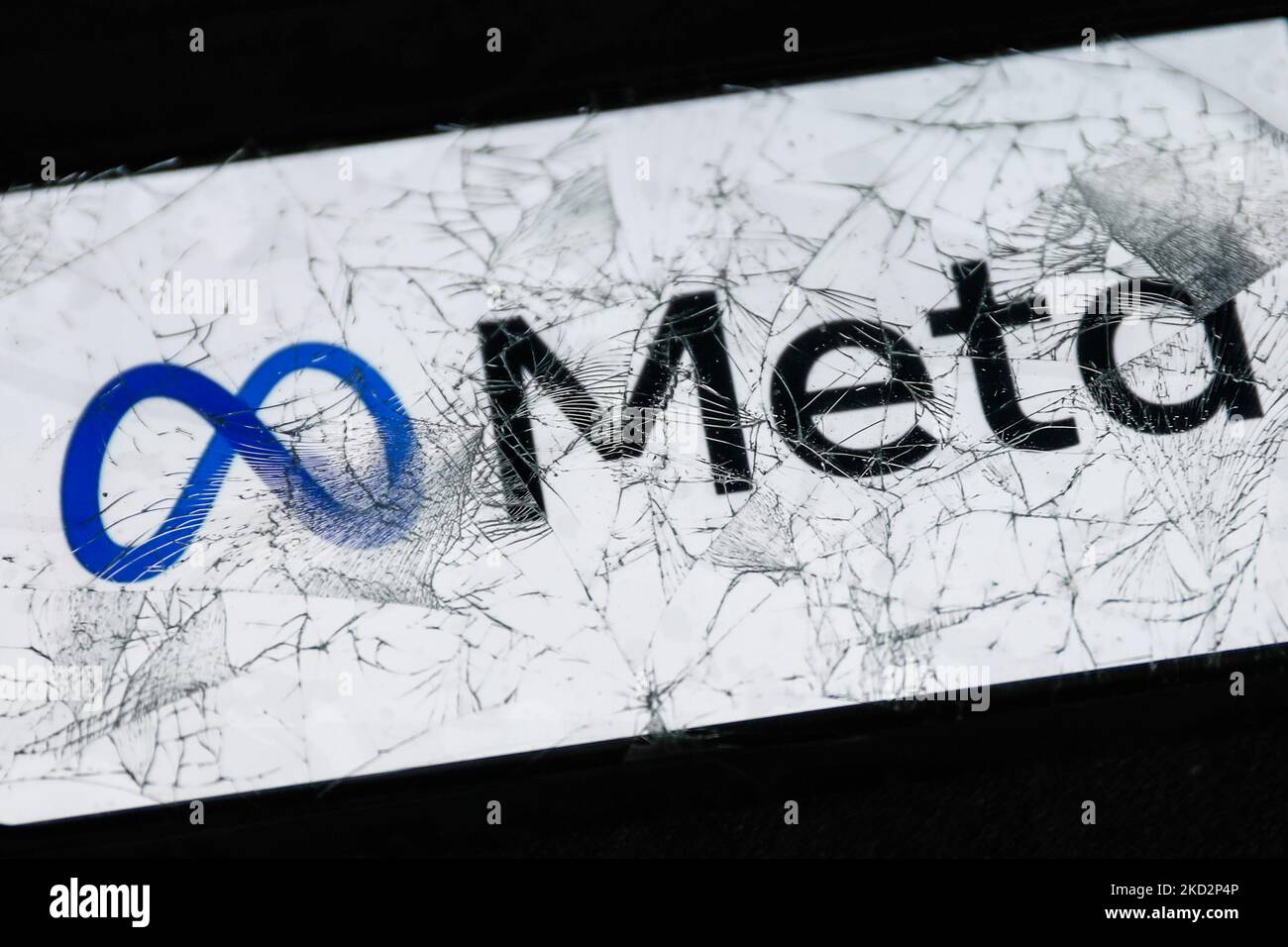Meta logo displayed on a phone screen is seen through a broken glass in ...