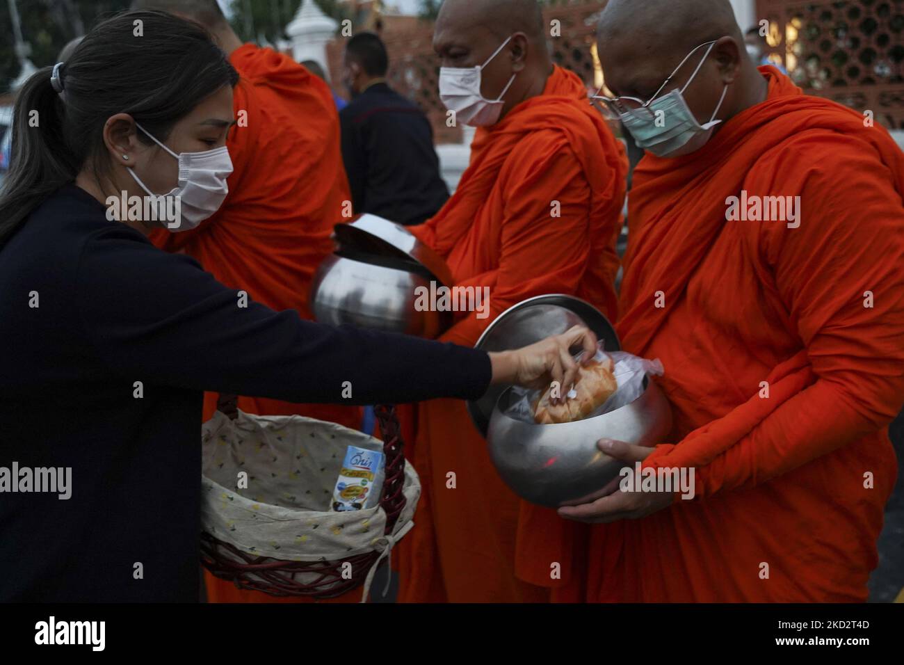 Thai Buddhist monks wearing protective face masks receive offerings ...