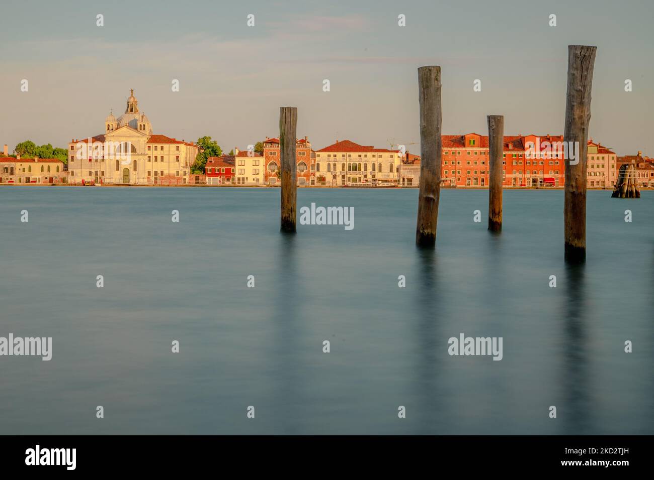 The wooden pilings on the water's surface with beautiful buildings in ...