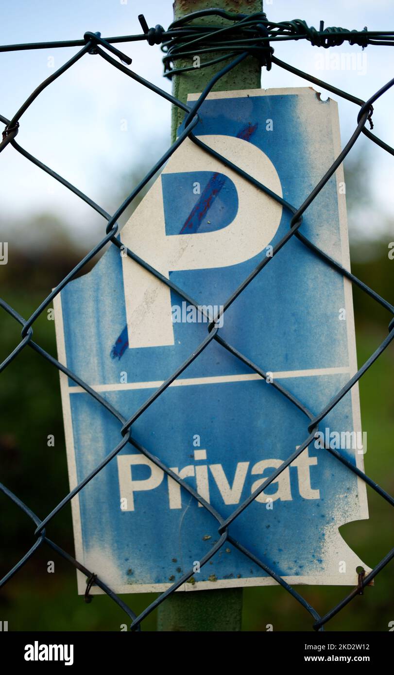weathered blue-white sign of a private parking site attached at a wire ...