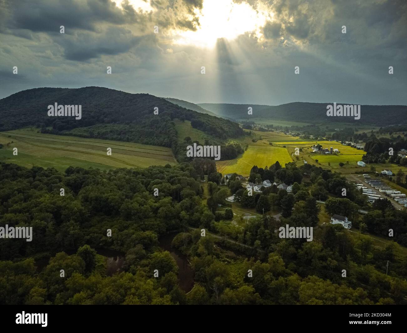 An aerial view of the green forested hillside with sun rays coming ...
