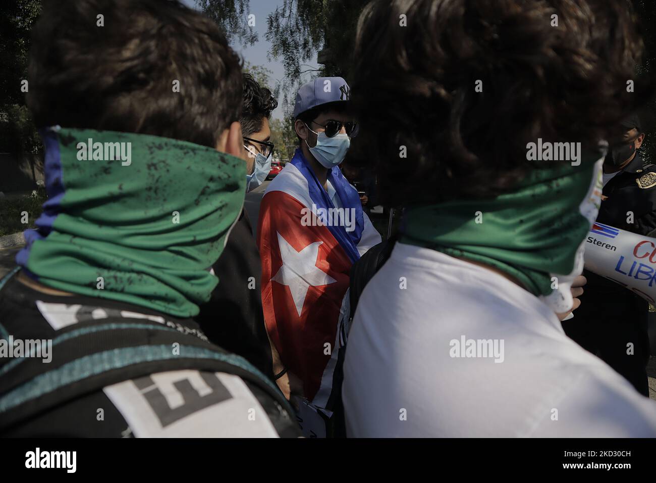 Members of the Cuban community in Mexico carry masks with the Cuban and ...