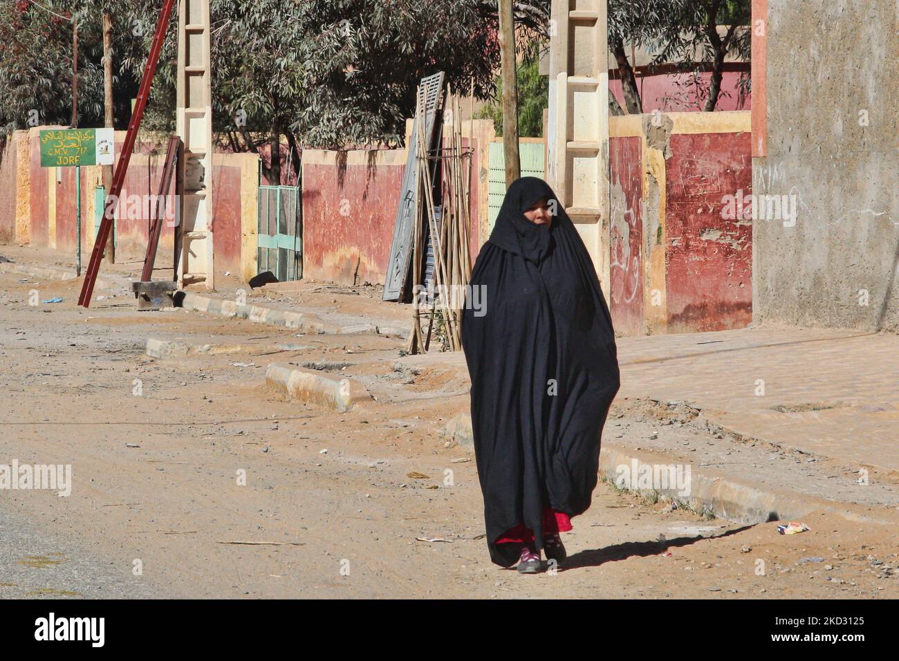 Woman (who is wearing a traditional black 'haik' body cloak) walking ...