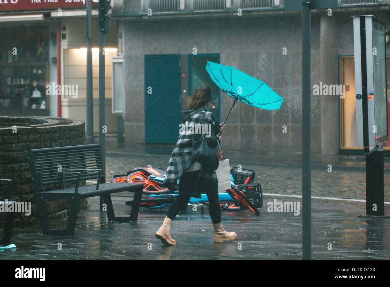 a woman struggle to walk in high wind and rain in front of Dom ...
