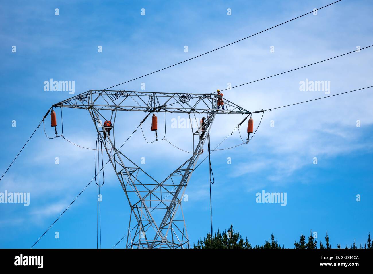 Men working atop an electricity transmission tower maintaining the ...