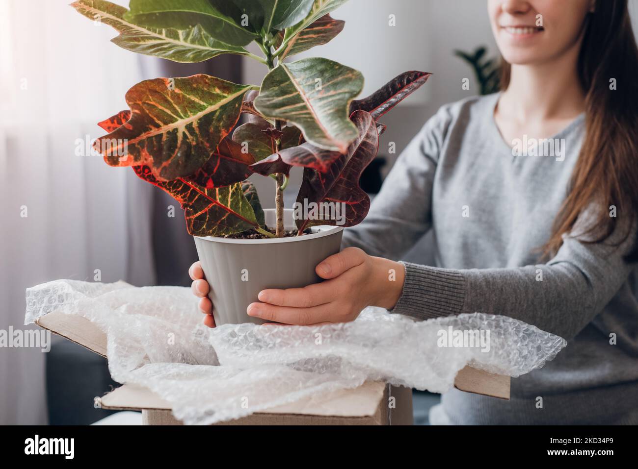 Close-up smiling young caucasian woman sitting on comfy sofa unpacking ...