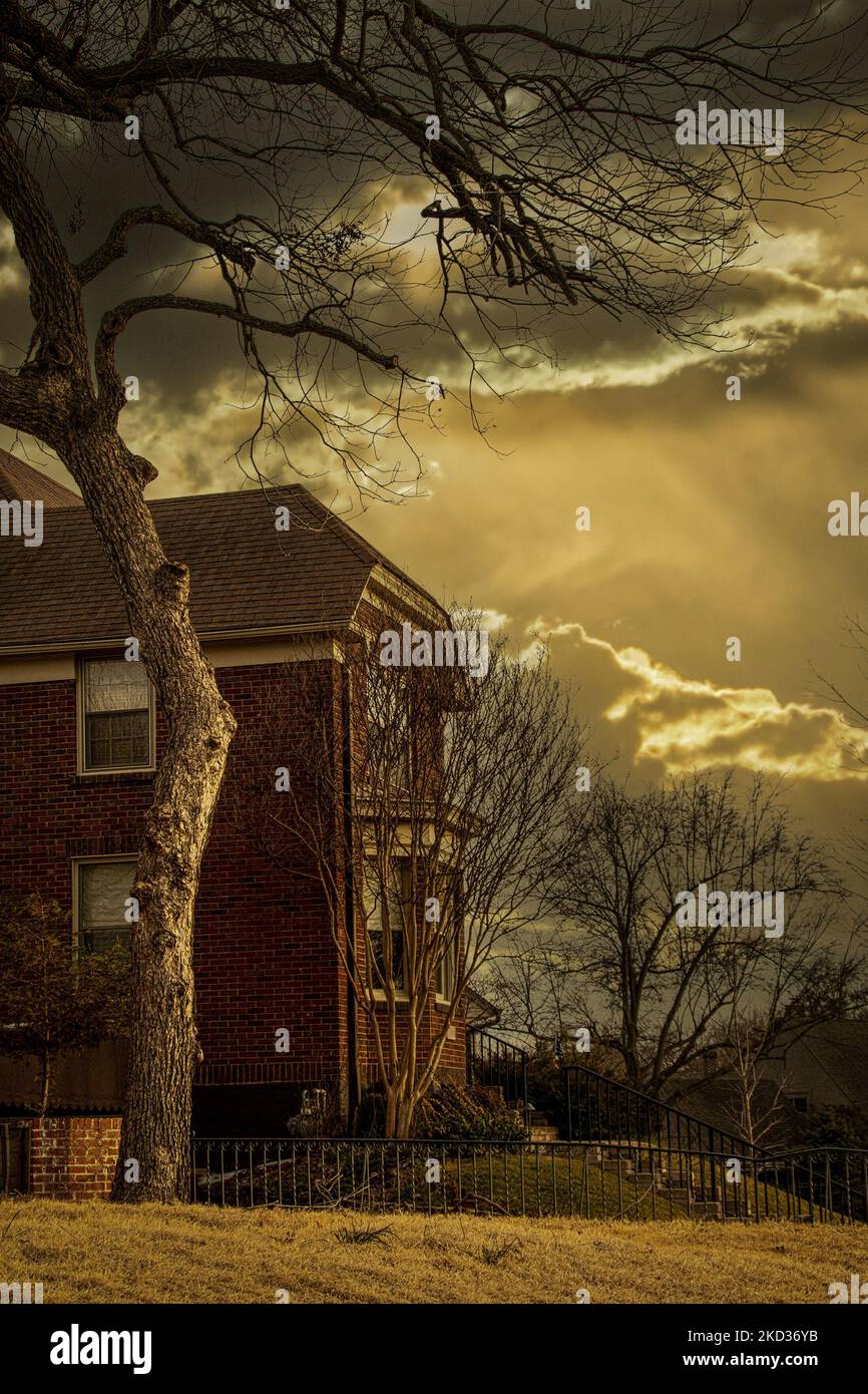 Dark spooky two story brick house with stark winter tree overhanging ...